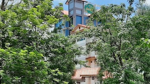 Um edifício com telhado de telhas vermelhas, rodeado por árvores verdes e exuberantes.