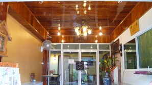 Uma área de recepção com teto de madeira, um ventilador, balcão de atendimento e uma janela ampla.