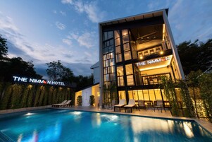 Um hotel moderno com piscina, área de estar externa e fachada bem iluminada.