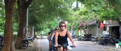 Rua arborizada com bicicletas estacionadas.