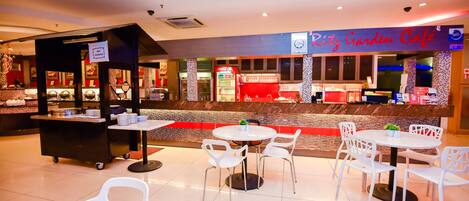 Um restaurante com placa vermelha e azul, cadeiras brancas e um balcão com refrigerador de Coca-Cola.