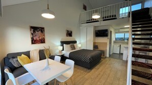 Uma sala de estar moderna com sofá, mesa de jantar, cadeiras, escada e área de cozinha.