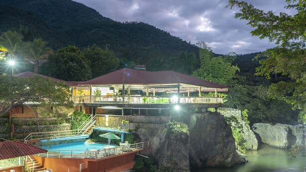 Um hotel com piscina, área externa para sentar e vista para uma paisagem montanhosa.