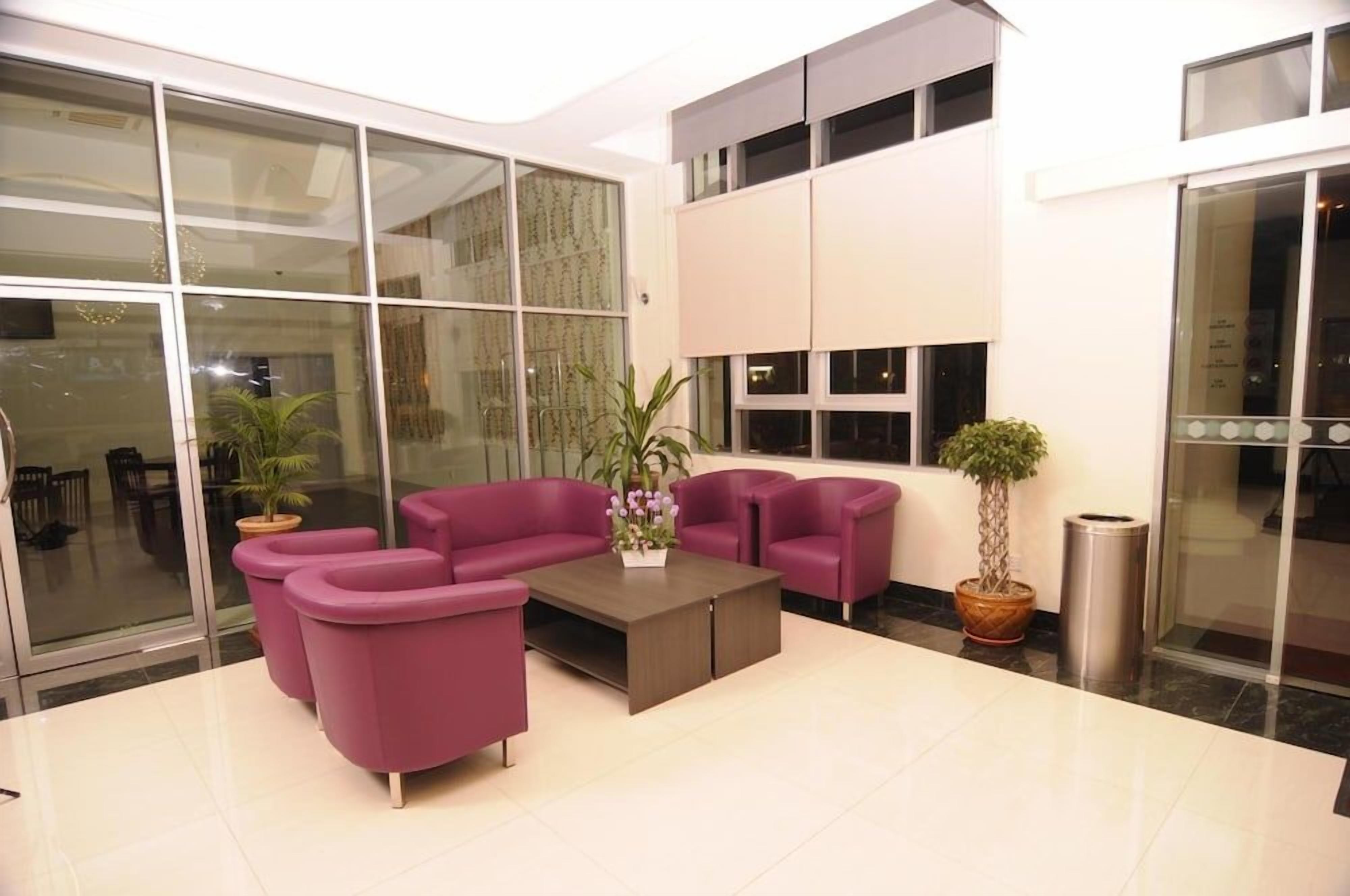 Um lobby moderno com área de estar, mesa de centro e plantas em vasos.