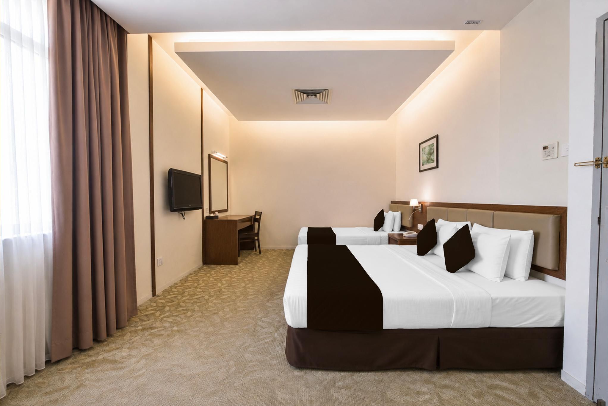 Quarto de hotel com cama, mesa de cabeceira, abajur, escrivaninha, cadeira e televisão.