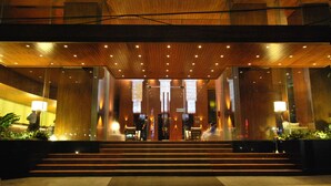 Entrada de hotel com fachada de madeira, degraus até as portas e acesso em vidro.