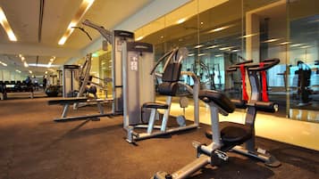 Uma academia com diversos equipamentos de exercício, um espelho e vista clara do interior.