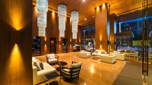 Um hall amplo com mobiliário moderno, janelas grandes e luminárias decorativas.