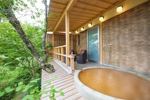 Um deck de madeira leva a uma área com hidromassagem, com uma parede em padrão herringbone e uma porta de vidro.