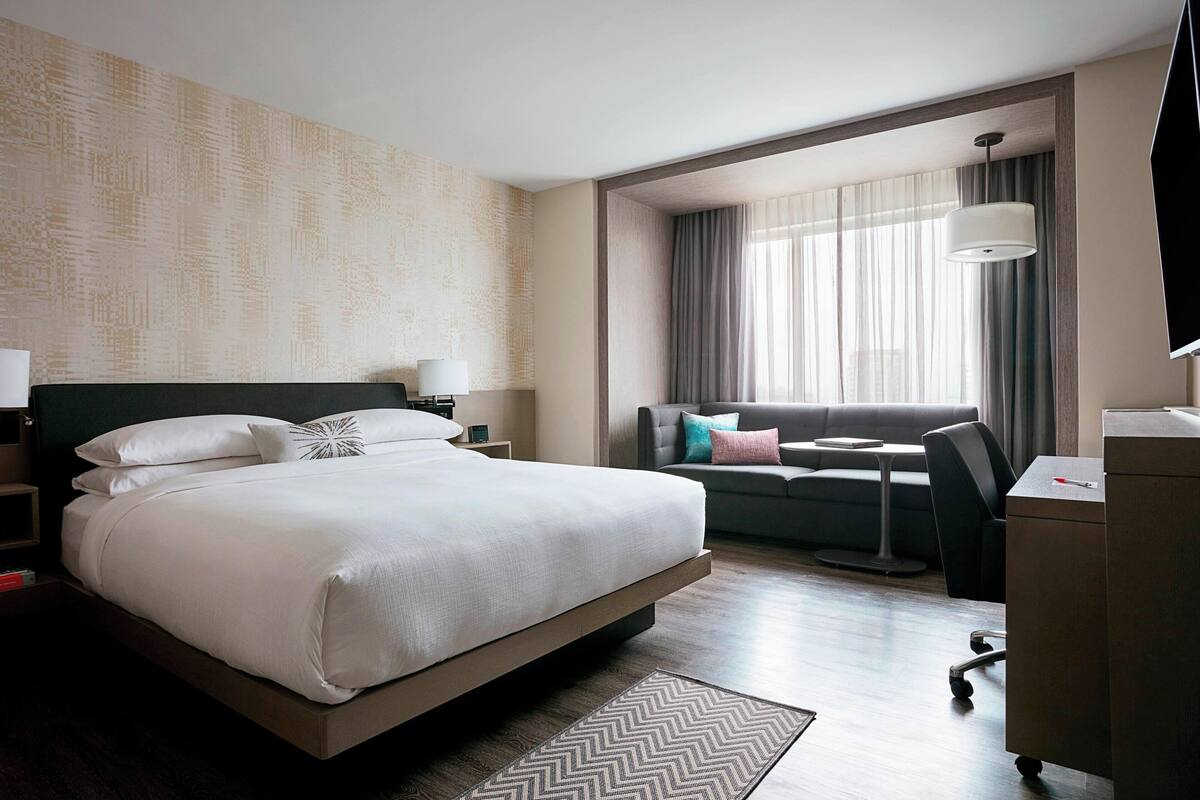 Quarto de hotel moderno com uma cama grande, uma escrivaninha e um sofá.