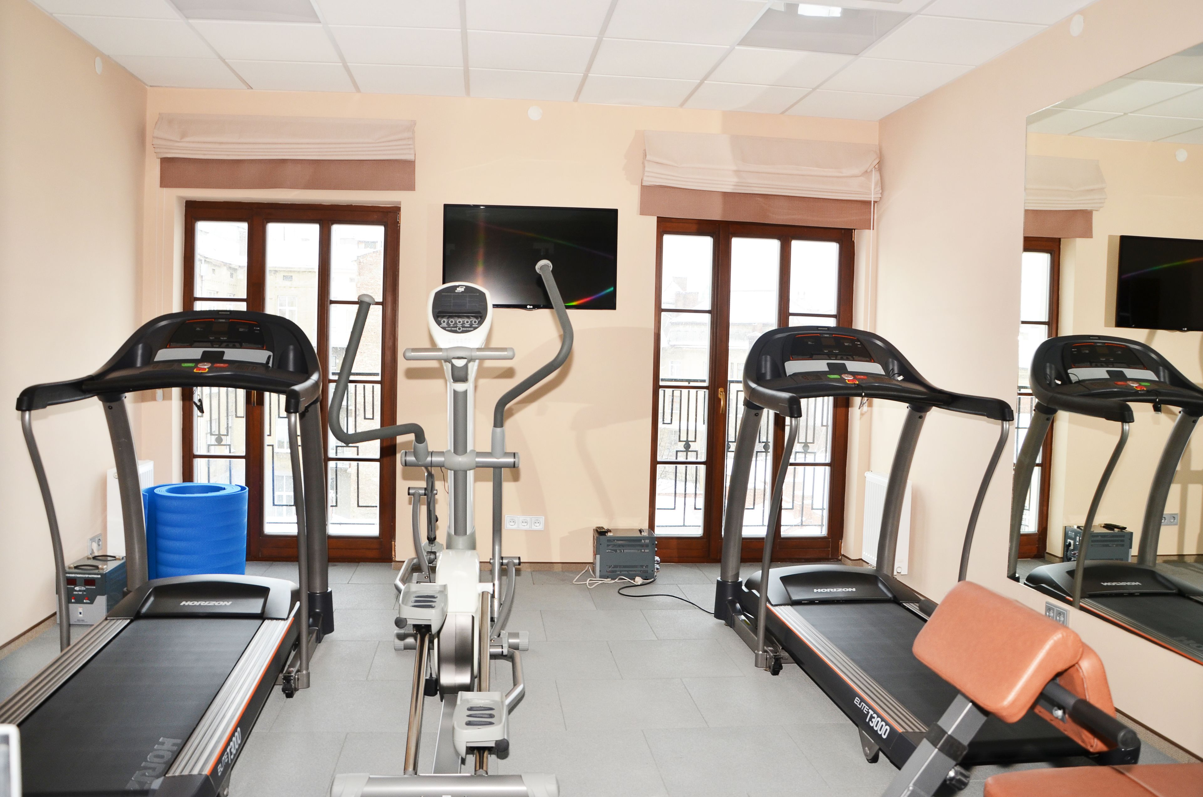 Uma academia com esteiras, elípticos e equipamentos de exercícios.