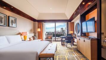 Quarto de hotel com uma cama grande, uma escrivaninha, uma televisão e vista para a cidade.