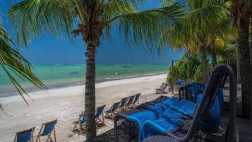 Na praia, areia branca, espreguiçadeiras, guarda-sóis