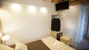 Quarto com cama, mesa de cabeceira, abajur e cabideiro.