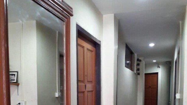 Um corredor com porta de madeira, espelho e chão ladrilhado.