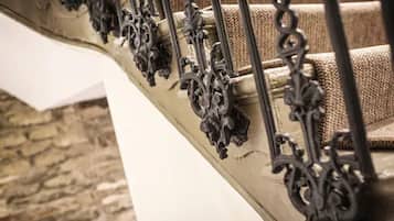 Escadaria com guarda-corpo de metal preto ricamente decorado e parede de pedra.