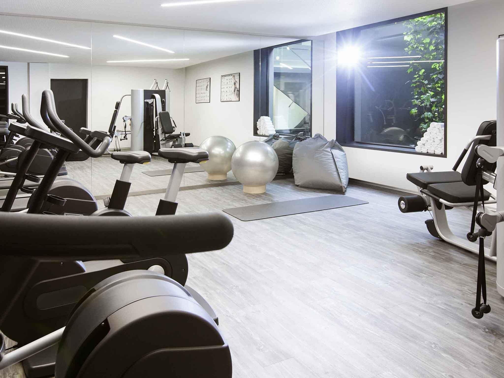Uma academia com esteiras, máquinas de peso e bolas de exercício.