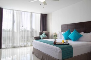 Quarto de hotel com uma cama grande, uma cadeira e vista para o exterior.