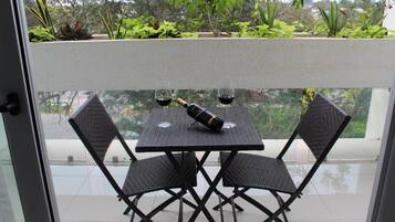 Varanda envidraçada com mesa, cadeiras, dois copos de vinho e uma garrafa.