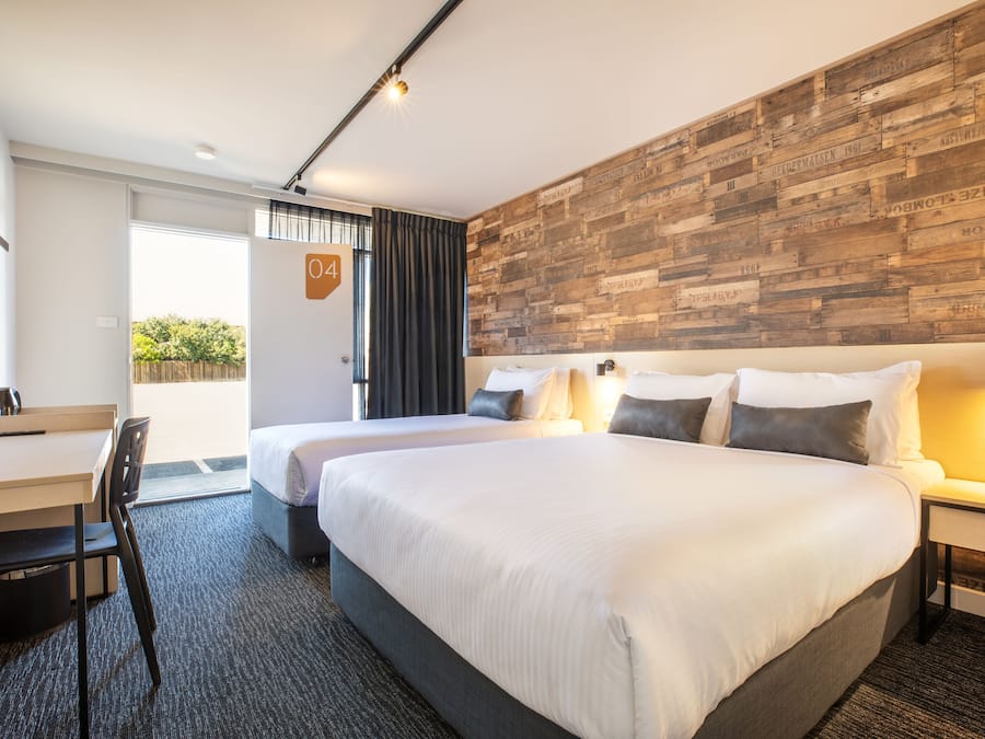 Quarto de hotel moderno com uma cama grande, uma escrivaninha e uma cadeira.