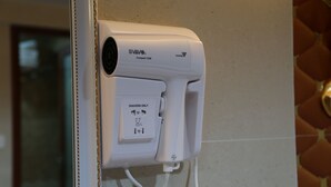 Um secador de cabelo branco SVAVO Compact 1300 fixado na parede com um cordão enrolado.