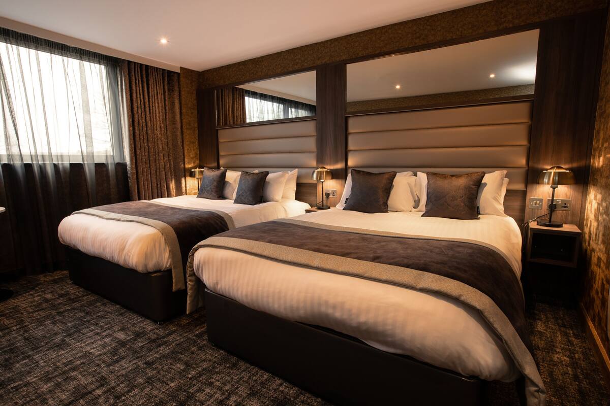 Quarto de hotel com duas camas, um espelho grande e piso coberto por carpete.