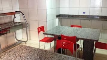 Cozinha com bancada de granito, cadeiras vermelhas e fogão de aço inoxidável.