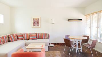 Uma sala de estar moderna com um sofá seccional, uma mesa de centro e uma área de jantar com cadeiras e mesa.