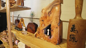 Uma prateleira de madeira com diversos objetos decorativos, incluindo uma peça de madeira entalhada com um orifício e uma pequena estatueta.