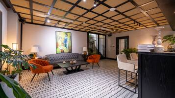 Uma sala de estar moderna com piso estampado, um sofá, duas poltronas, uma mesa de centro e um vaso decorativo.