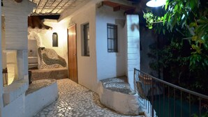 Um edifício com entrada em azulejos, escadaria com degraus em mosaico e varanda com grade.