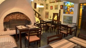 Uma sala de jantar com lareira de tijolos, mobiliário de madeira e escada que leva a um andar superior.