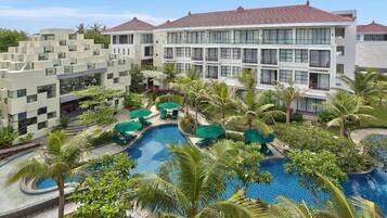 Hotel com piscina rodeada por palmeiras e espreguiçadeiras.