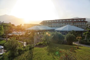 Um hotel com vários edifícios, um jardim bem cuidado e montanhas ao fundo.