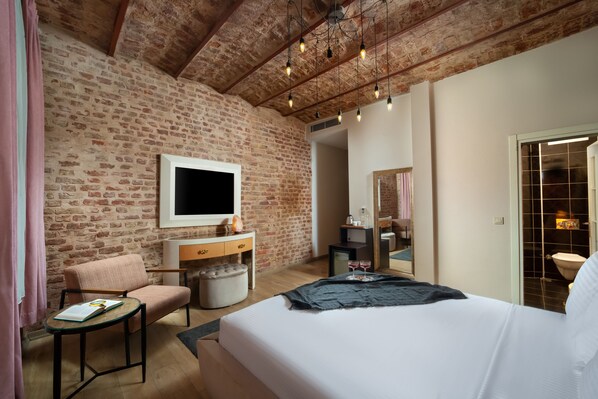 Quarto com parede de tijolos, cama, televisão, cômoda e cadeira.