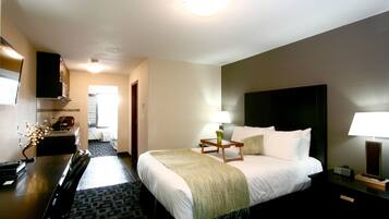 Quarto de hotel com cama, mesa de cabeceira, abajur e escrivaninha com cadeira.