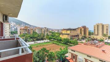 Zona residencial com vários edifícios de apartamentos, um jardim no terraço e vista para uma paisagem montanhosa.
