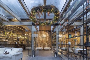 Um interior moderno com teto de vidro, vigas de madeira, um espaço de estar acolhedor e um bar com prateleiras.