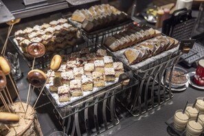 Uma variedade de sobremesas, incluindo bolos e doces, dispostas em bandejas.