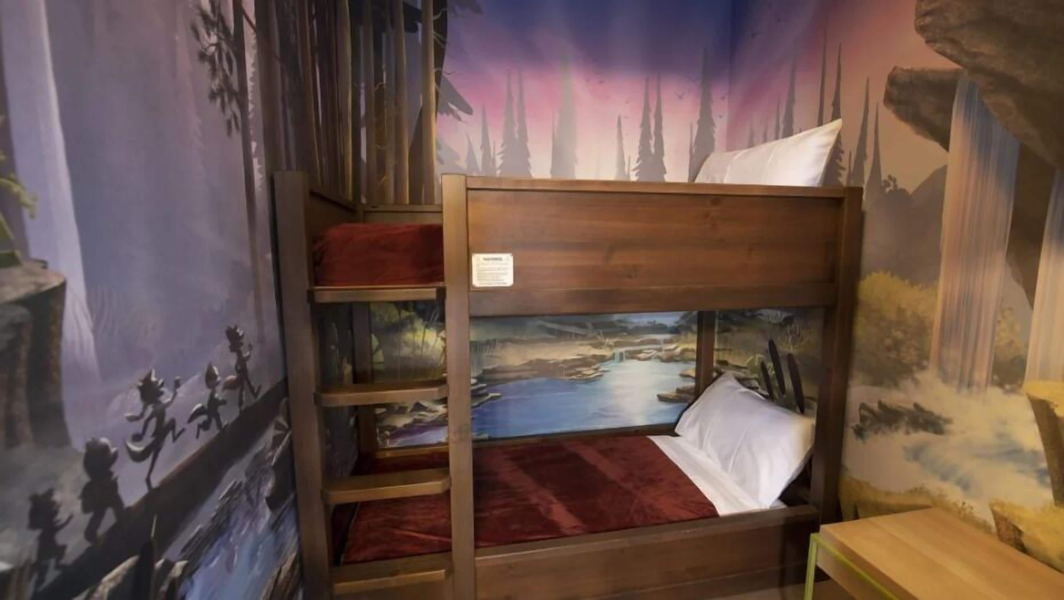 Uma cama beliche com um mural de uma cena de floresta na parede ao fundo.