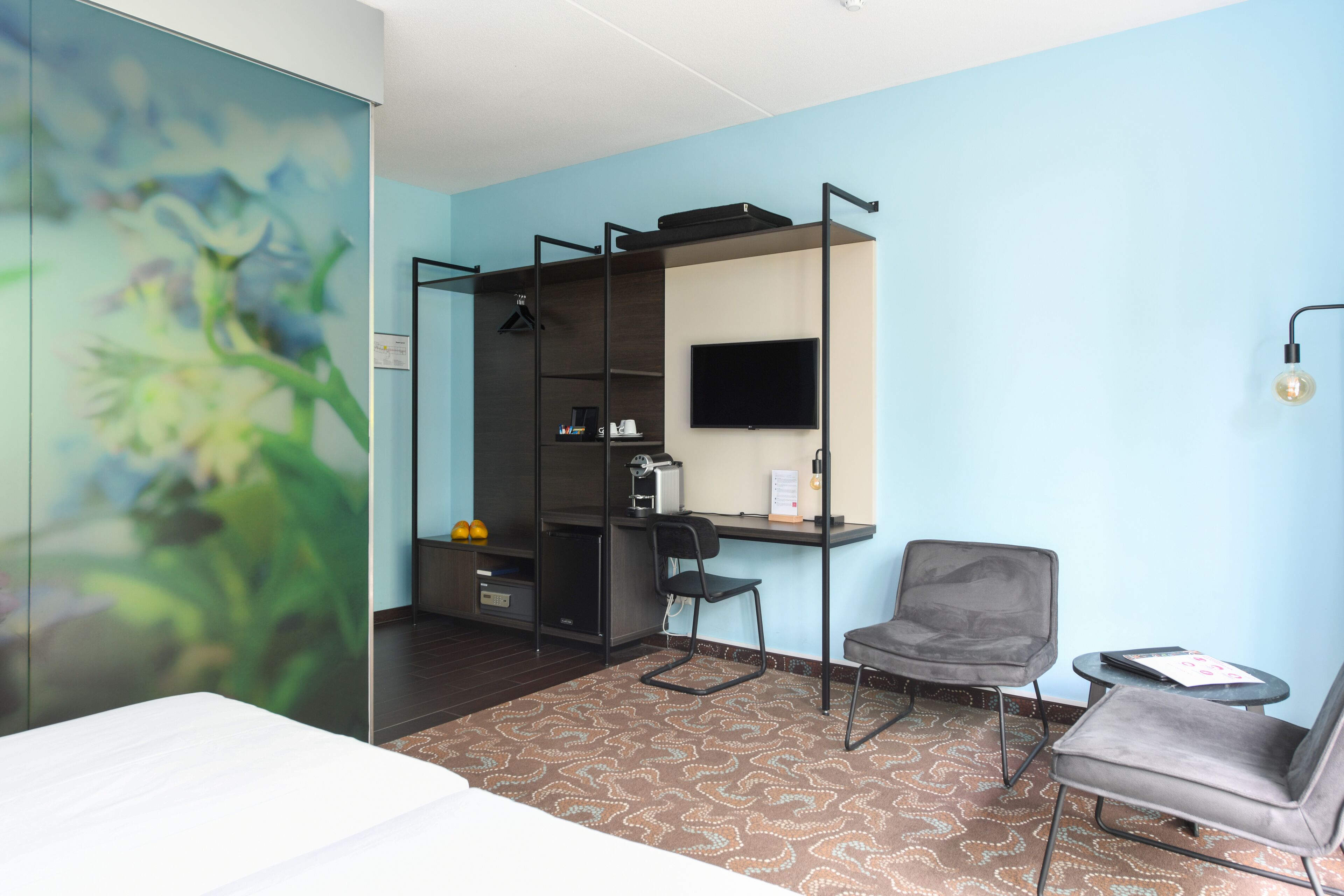 Quarto com cama, escrivaninha, cadeira, televisão e guarda-roupa.