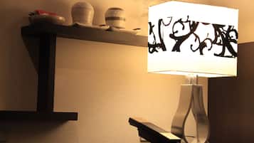 Uma luminária moderna com design preto singular na cúpula, colocada sobre uma mesa de madeira ao lado de um telefone.