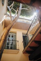 Uma escadaria com corrimão de metal, uma árvore com luzes de fada e uma janela com vista para o exterior.