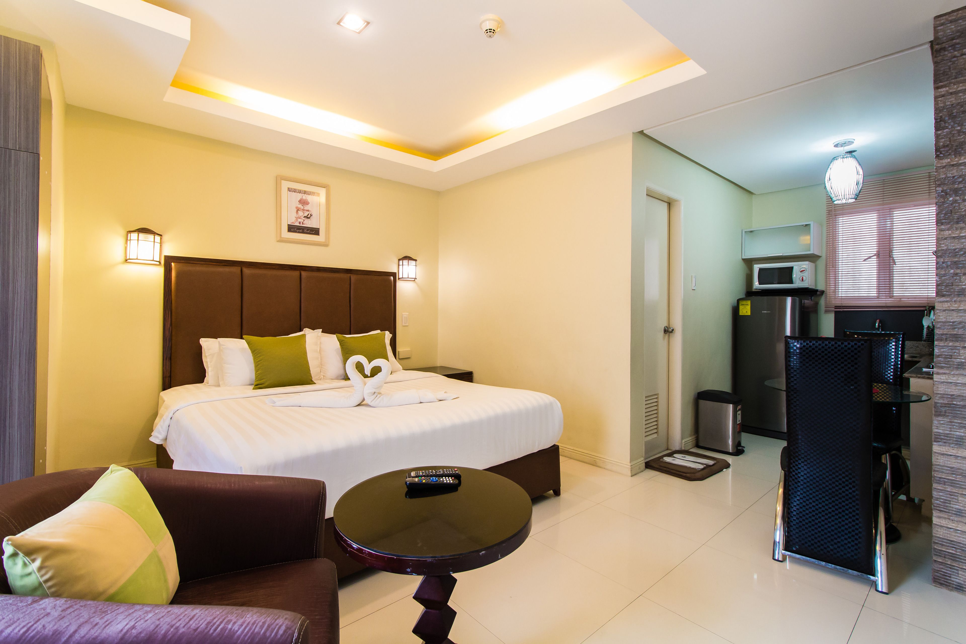 Quarto de hotel com uma cama, um sofá, uma mesinha, micro-ondas e frigorífico.