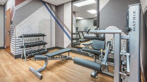 Uma academia com equipamentos de musculação, halteres e esteiras.
