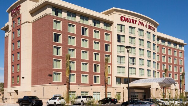 Um hotel Drury Inn & Suites com fachada de tijolos, várias janelas e céu claro.