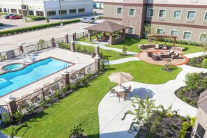 Área de piscina com hidromassagem, espreguiçadeiras e um espaço de estar coberto.