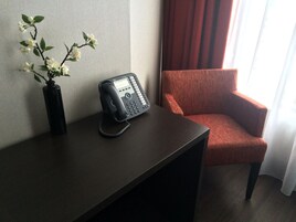 Quarto de hotel com escrivaninha, telefone e cadeira.