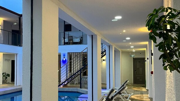 Área à beira da piscina com espreguiçadeiras, uma escadaria e vista para a piscina.