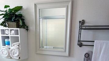 Casa de banho com lavatório assentado, porta-toalhas, prateleira com artigos de higiene e espelho.